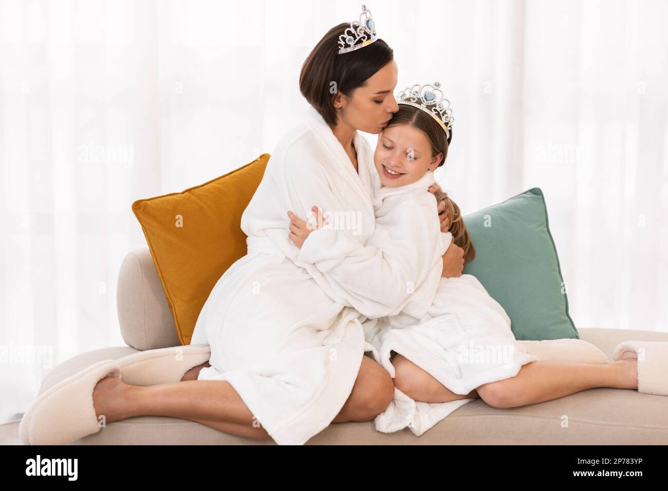 Mom And Daughter Wearing White Bathrobes And Toy Crowns Hugging At Home Stock Photo - Alamy
