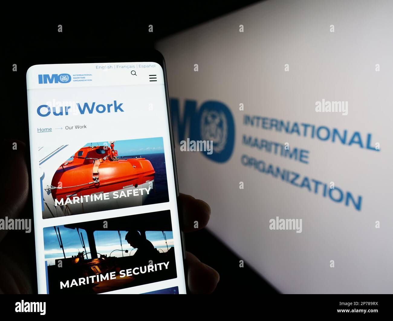Person holding cellphone with web page of International Maritime ...
