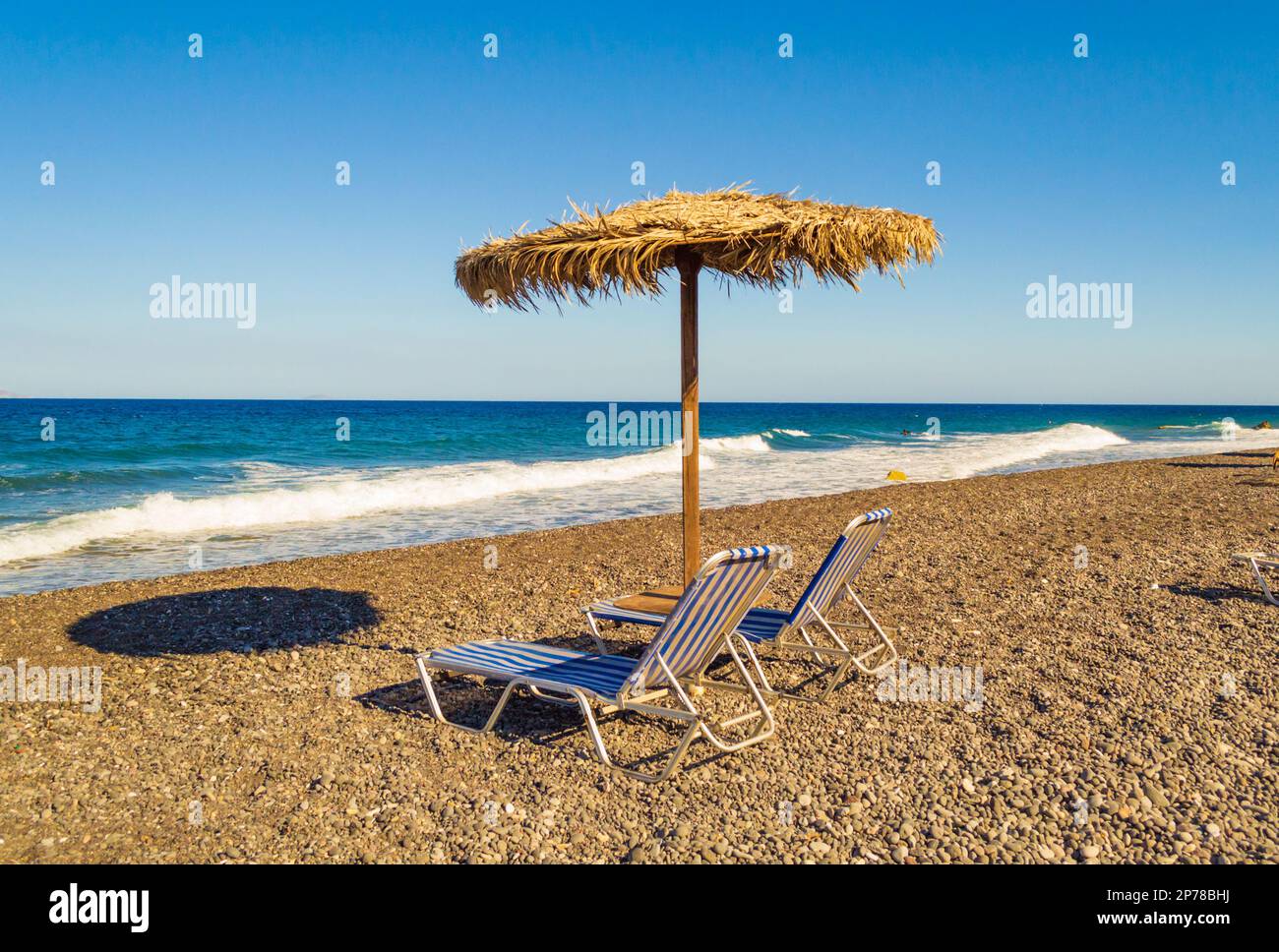 reed umbrella and two empty sunbeds at the Aegean sea coast , Black ...