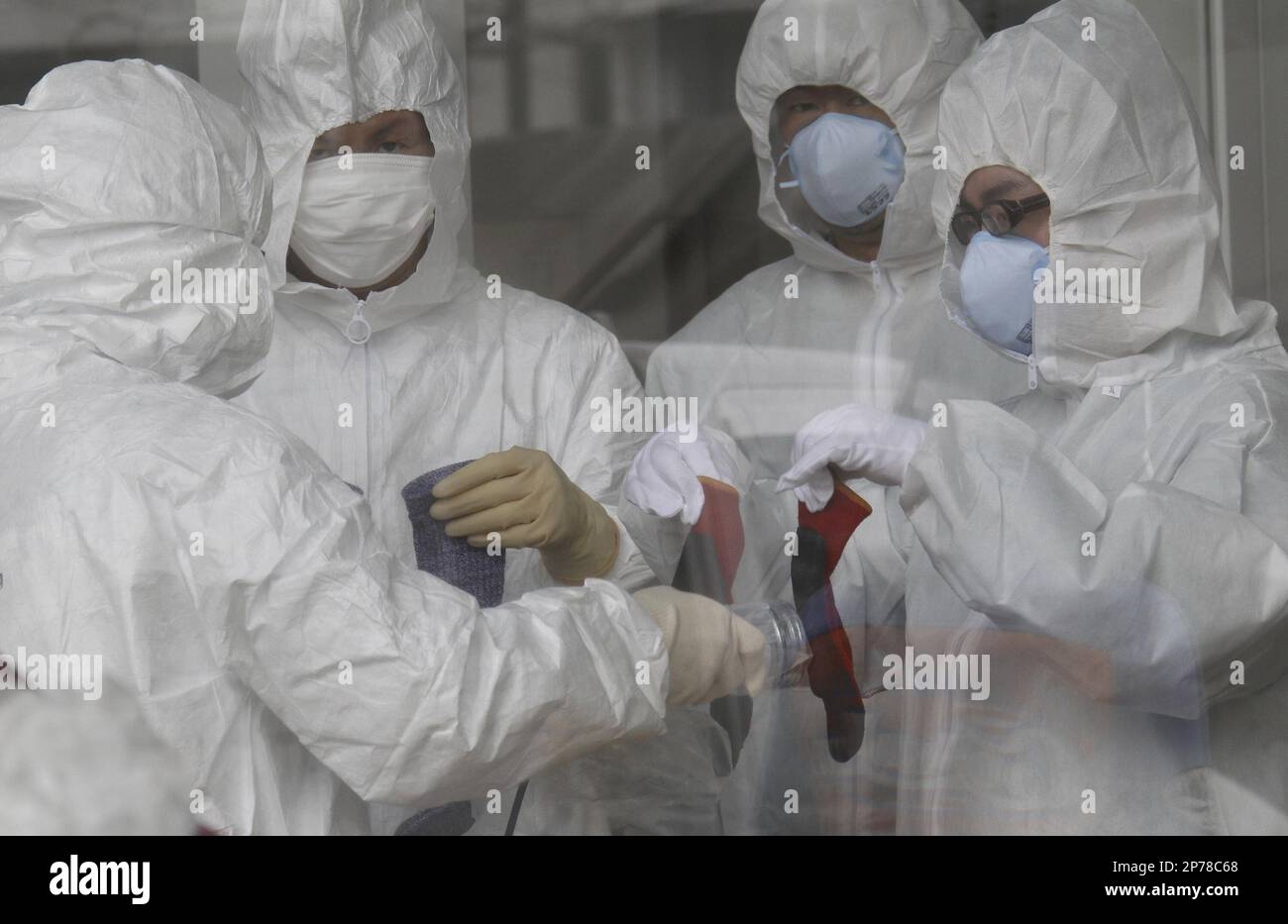 Workers in protective gear check gloves for radiation contamination in ...
