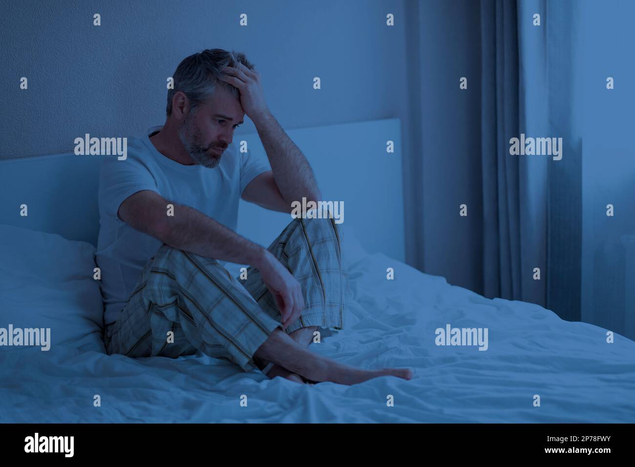 Stressed middle aged man sitting on bed at night, home inteior Stock ...