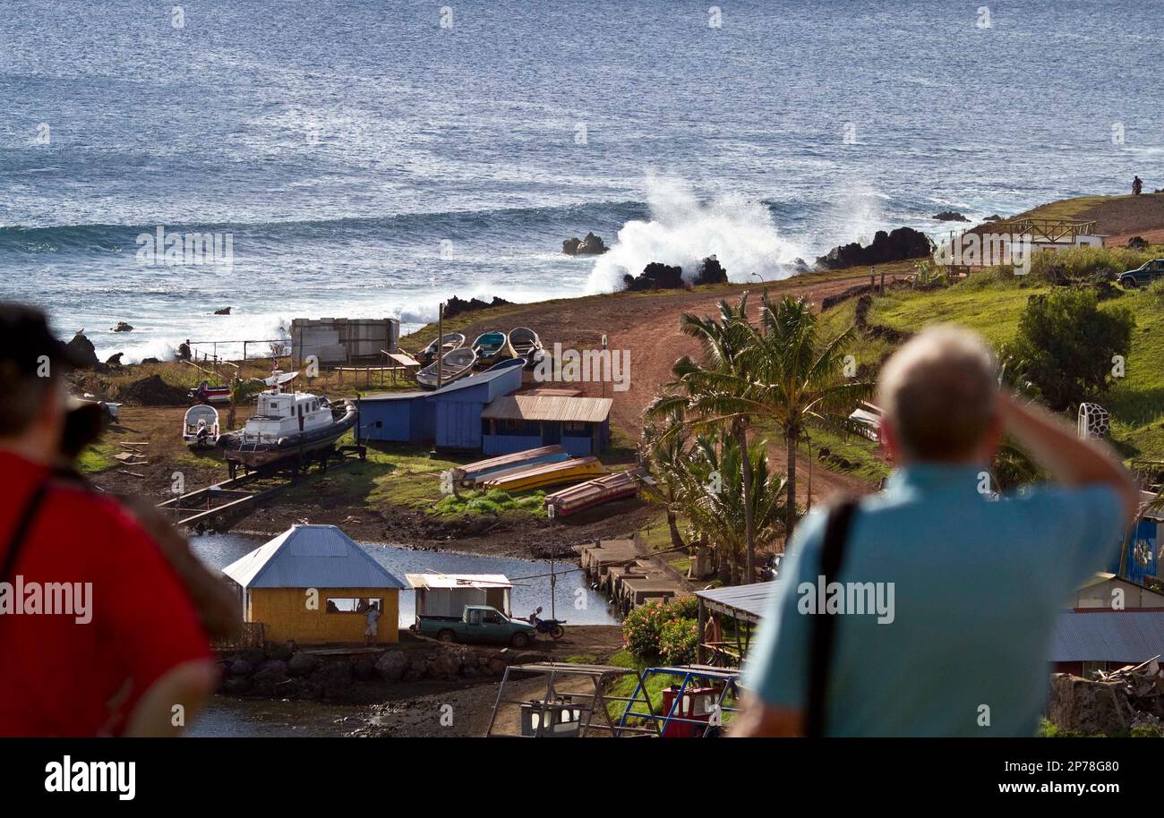 People watch from a hill top as waves crash into Hanga Roa harbour ...