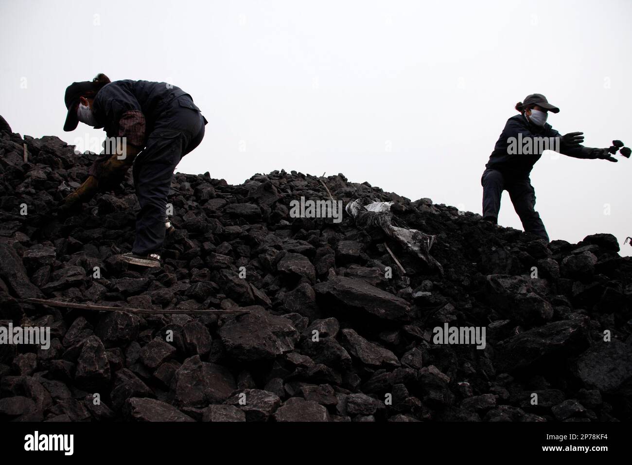 Female workers collect coal at a coal mine in Huaibei in central China ...