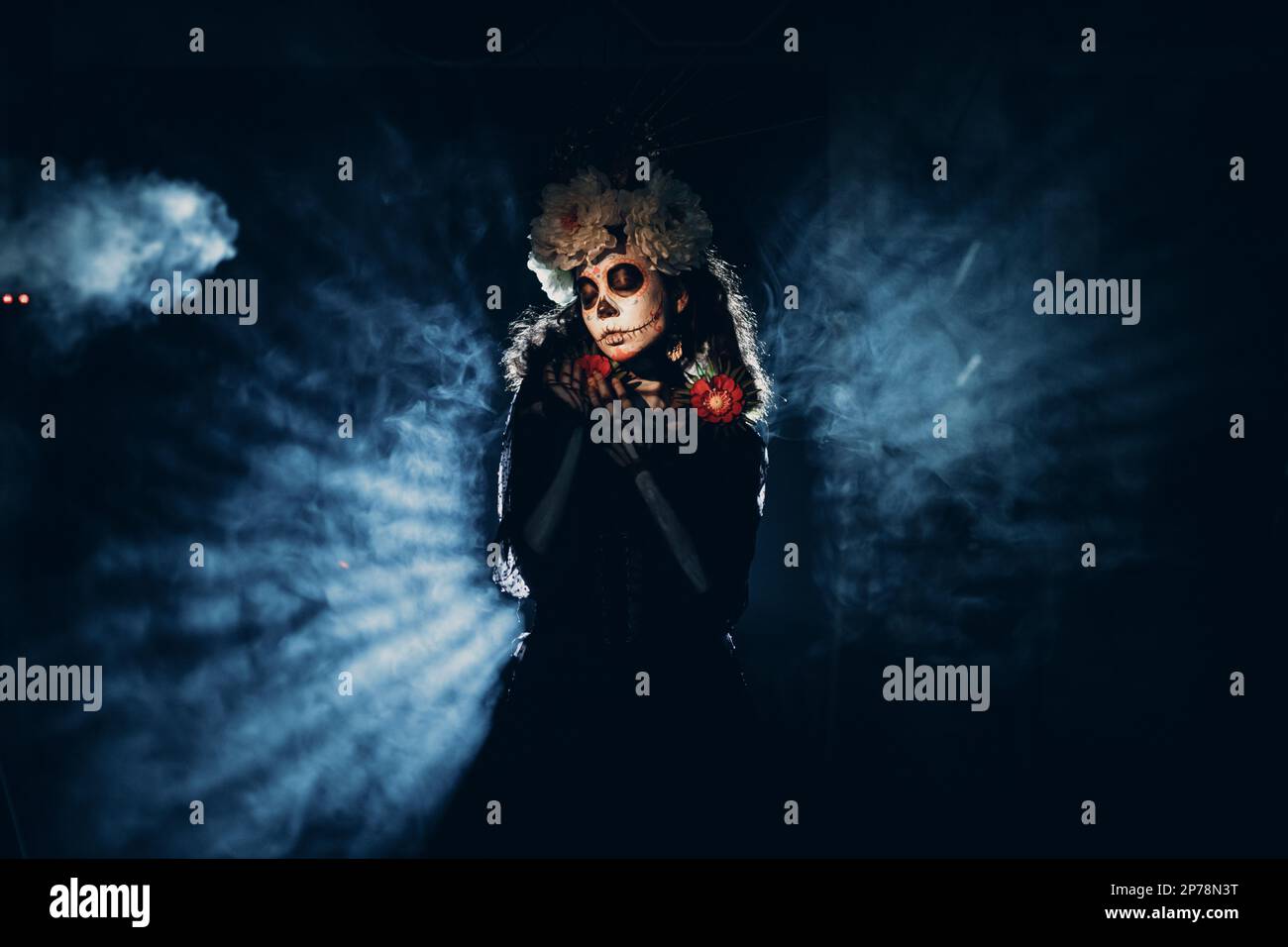 Woman with mexican skull halloween makeup in dark with backlight rays ...
