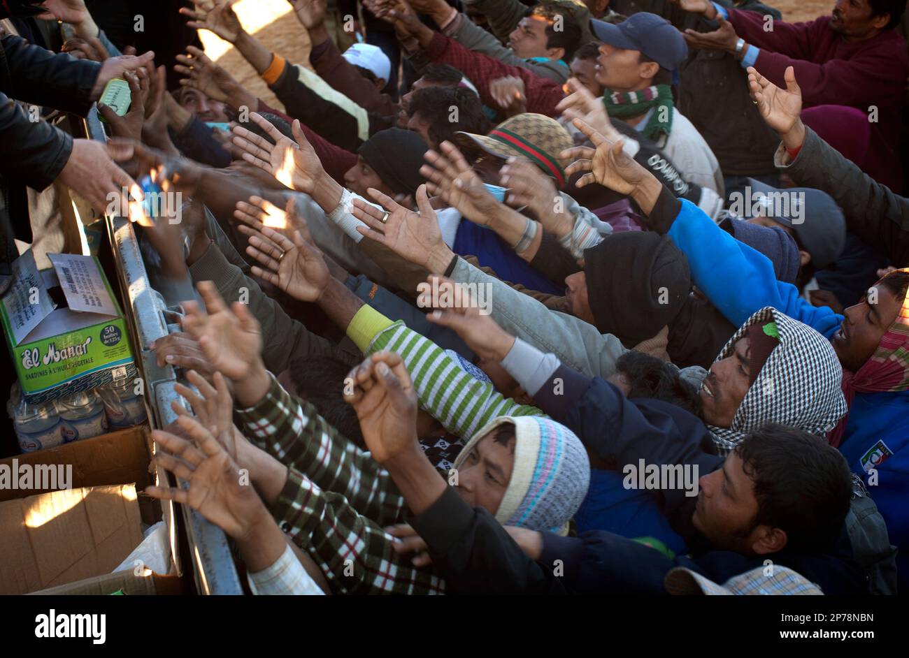 Men try to reach food during a food and supplies distribution in a ...