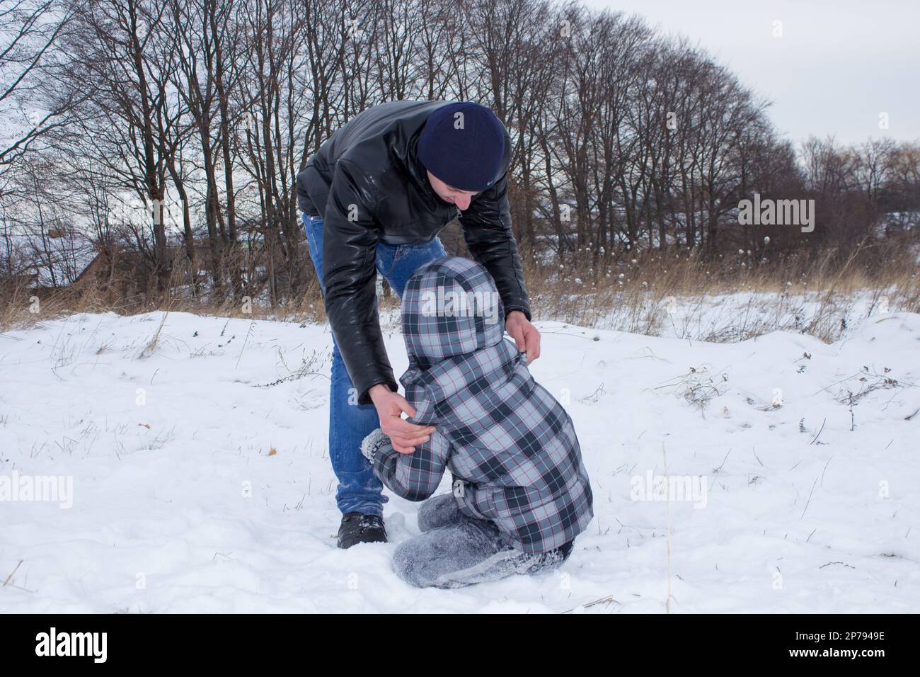 a young boy helps the little one get up from the snow Stock Photo - Alamy