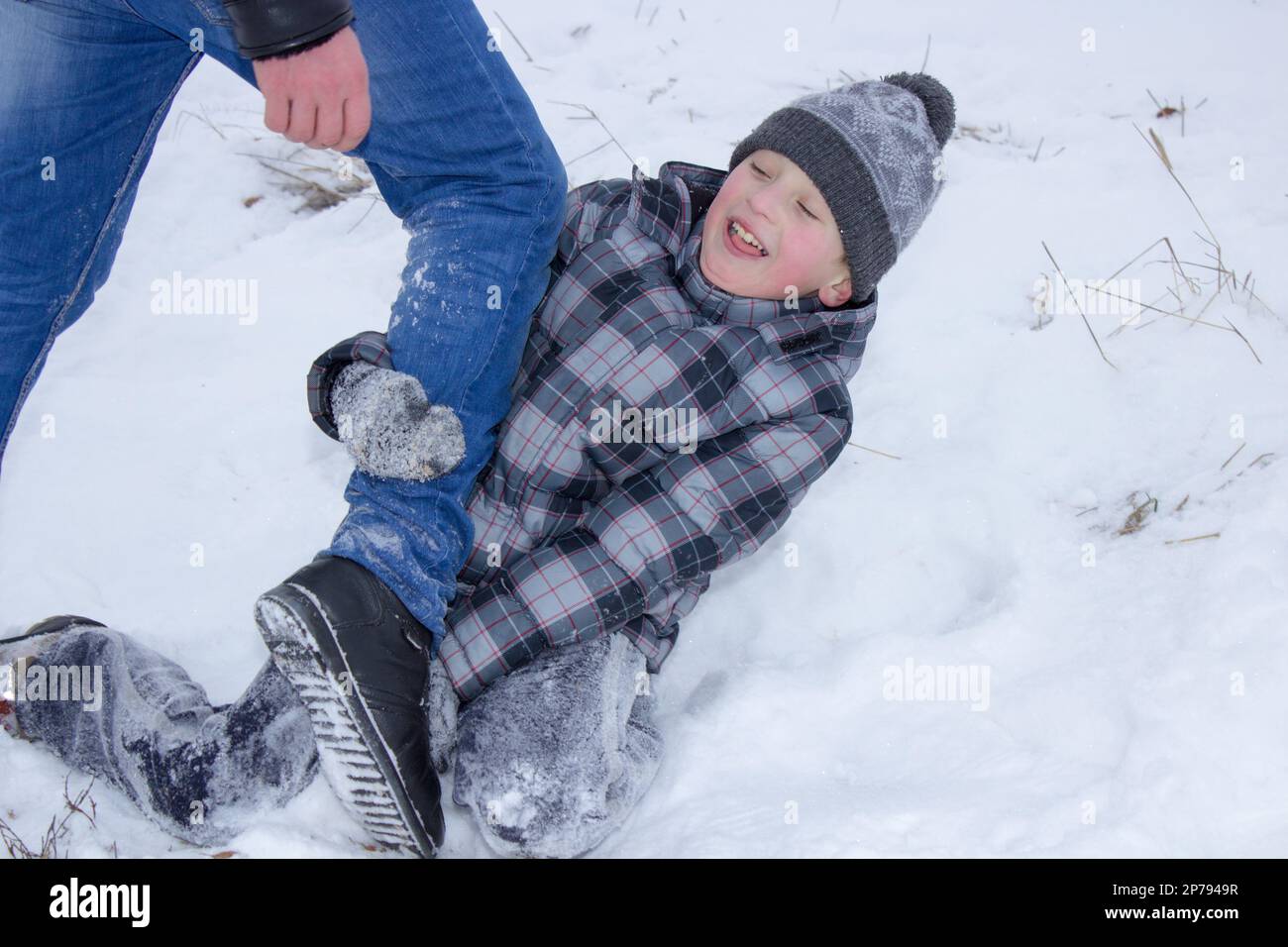 Winter games in the snow boy keeps behind the elder brother's leg Stock ...