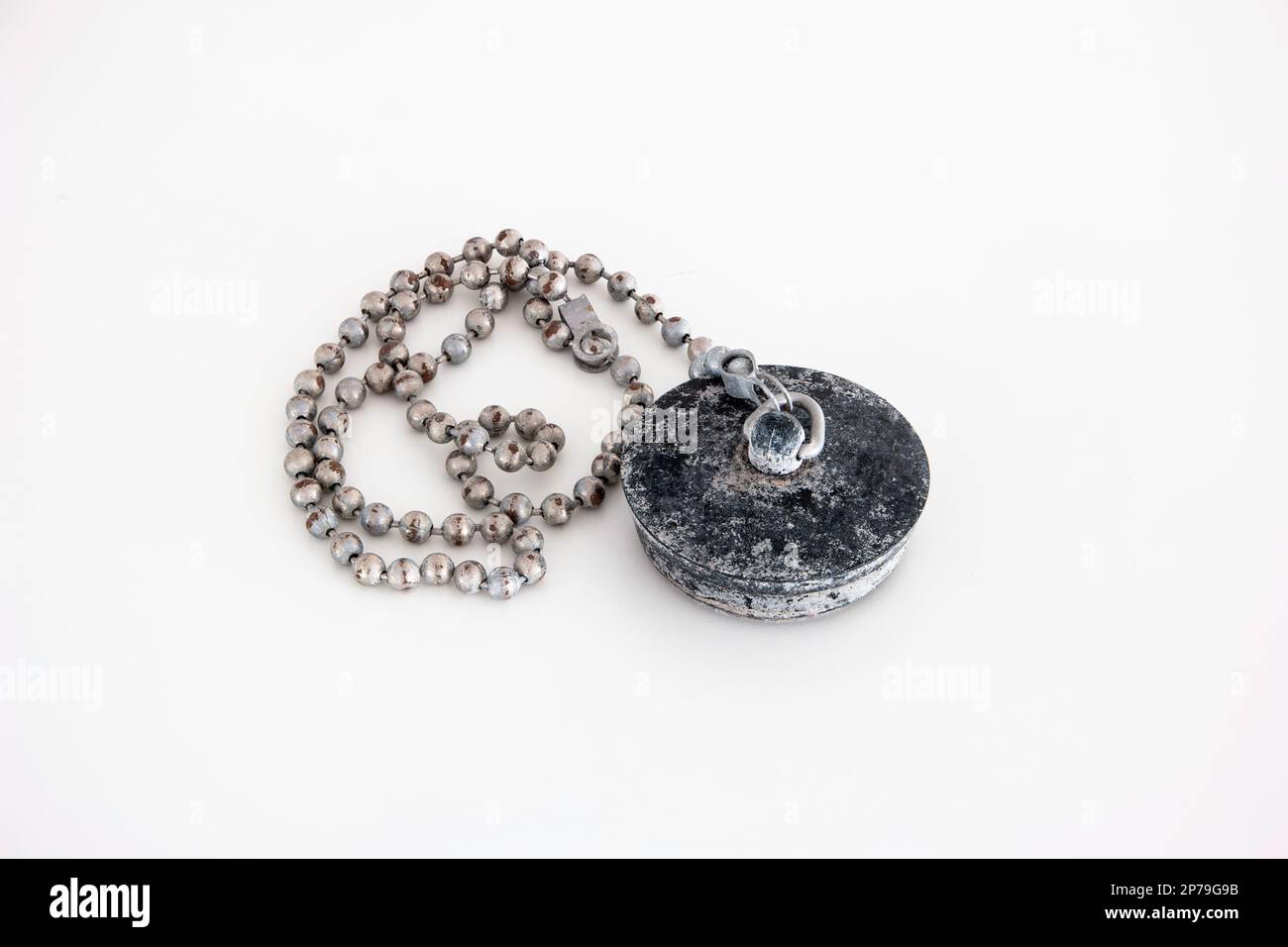 Old dirty limestone scale covered bathtub rubber plug and chain close ...