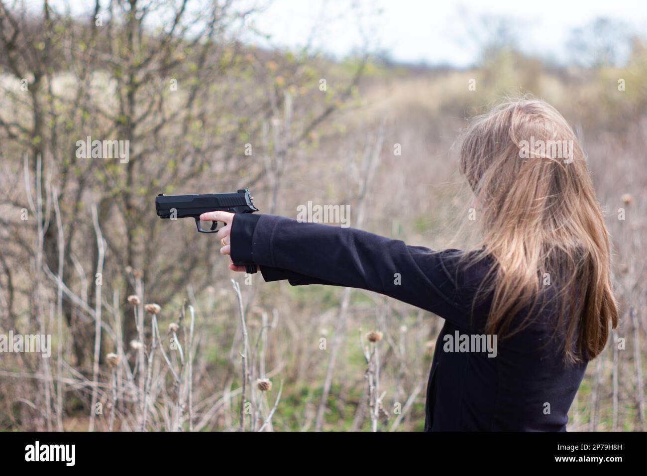 Young female arms and hands aiming a hand gun in self-defence training ...