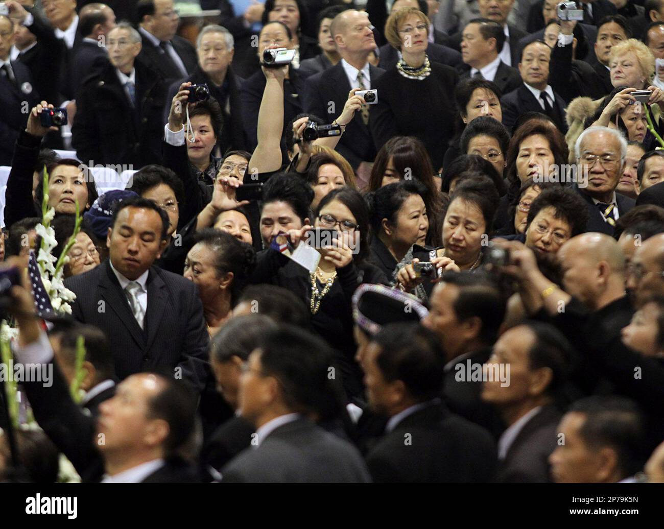 People strain to see and photograph the entering of the casket at the ...