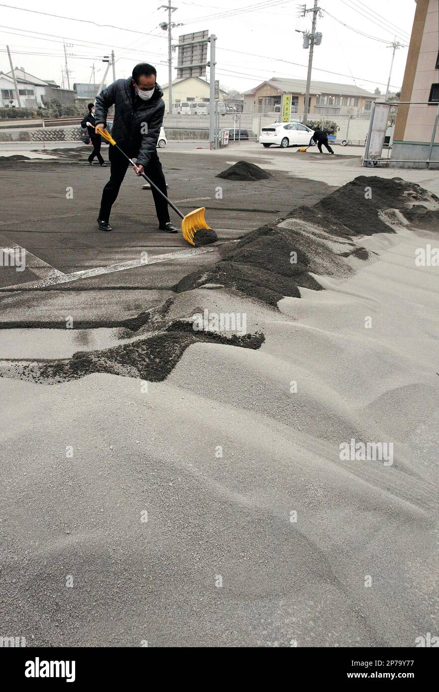 Compnay employees are cleaning up ash on parking lot during an eruption ...