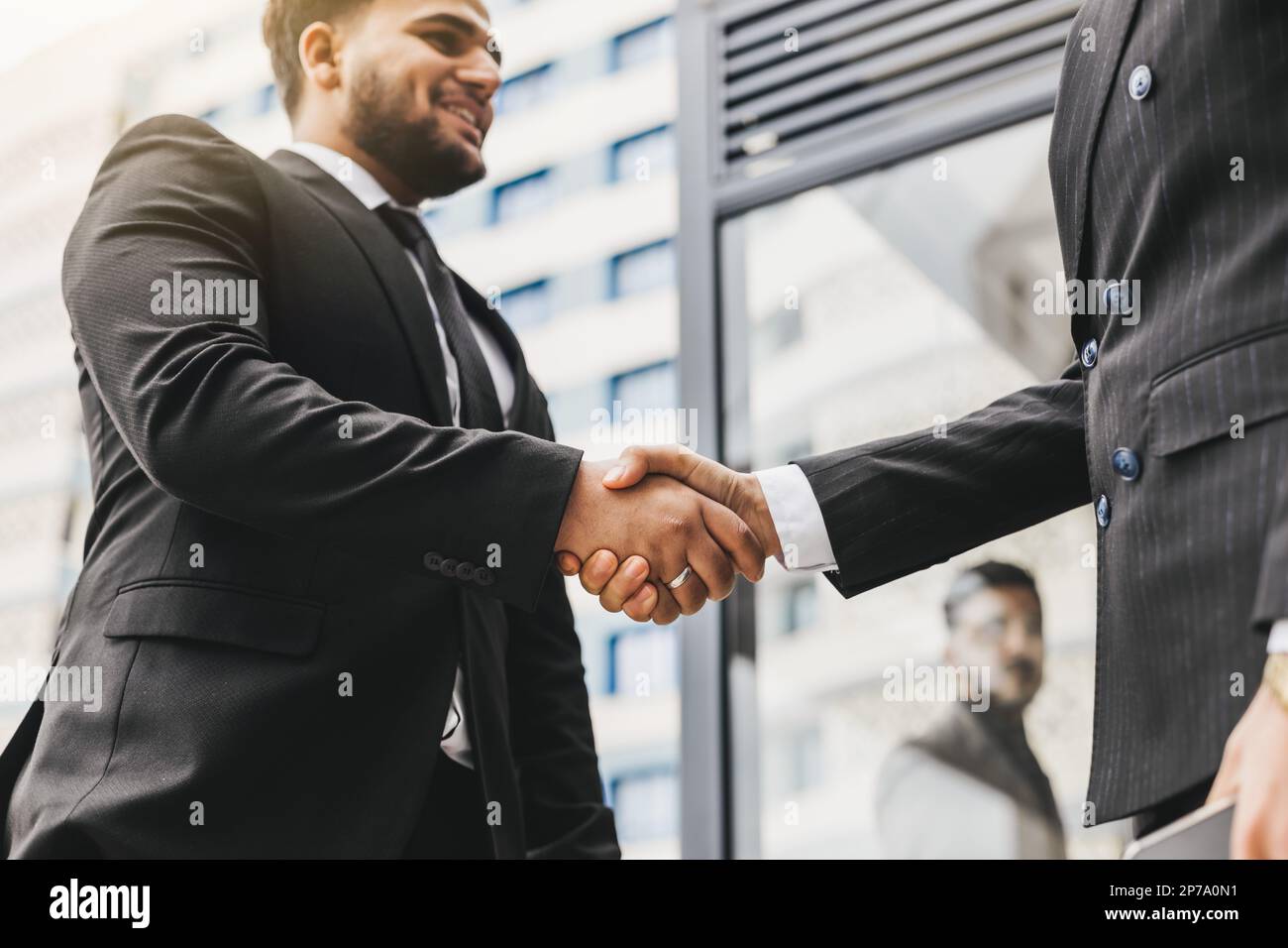 Business people outdoor meeting. Two men in suits hold out their hands ...