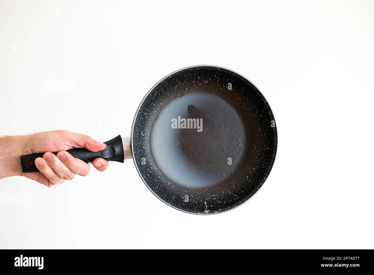 Caucasian male hand holding an old frying pan stained with hardened ...