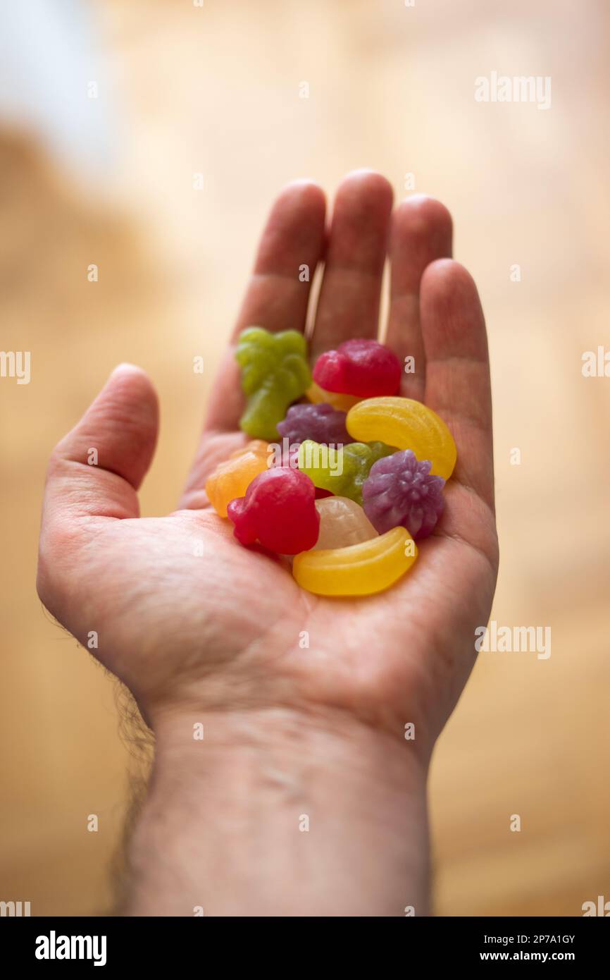 Variety of colorful gummy jelly bonbons held in hand by Caucasian male ...