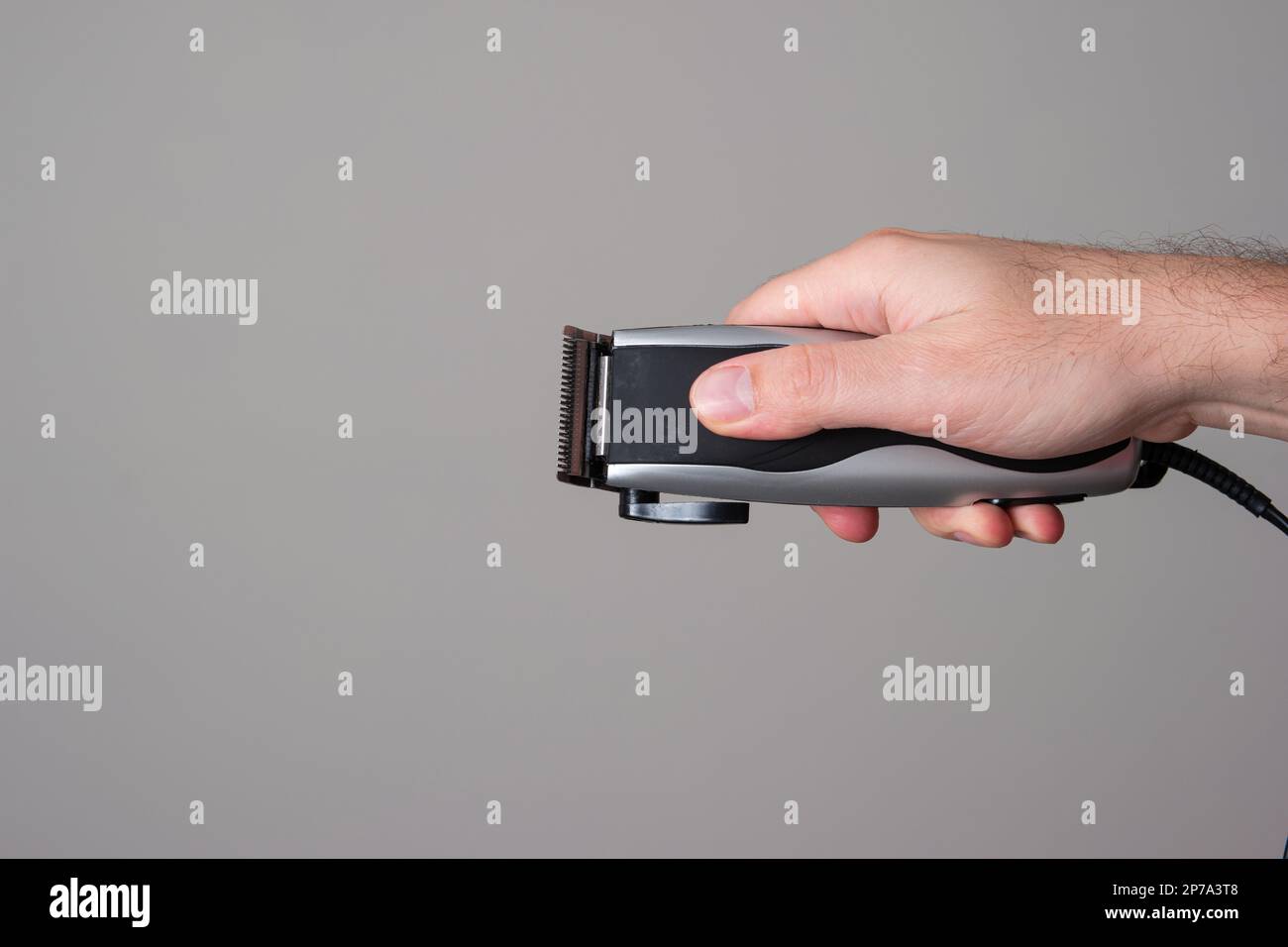 Electric hair trimmer held in hand by Caucasian male hand close up shot ...