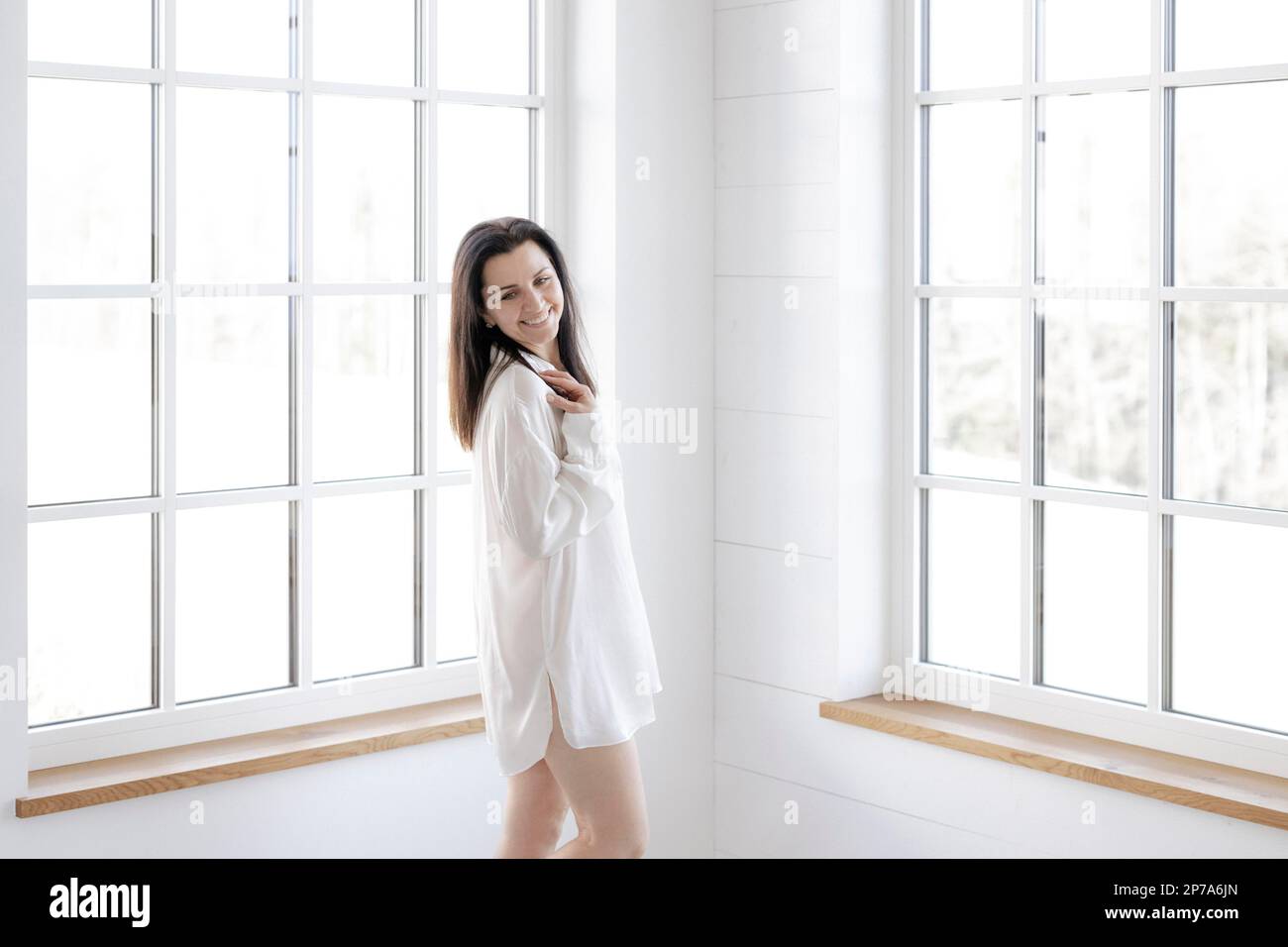 Attractive woman in a white shirt in front of a window Stock Photo - Alamy