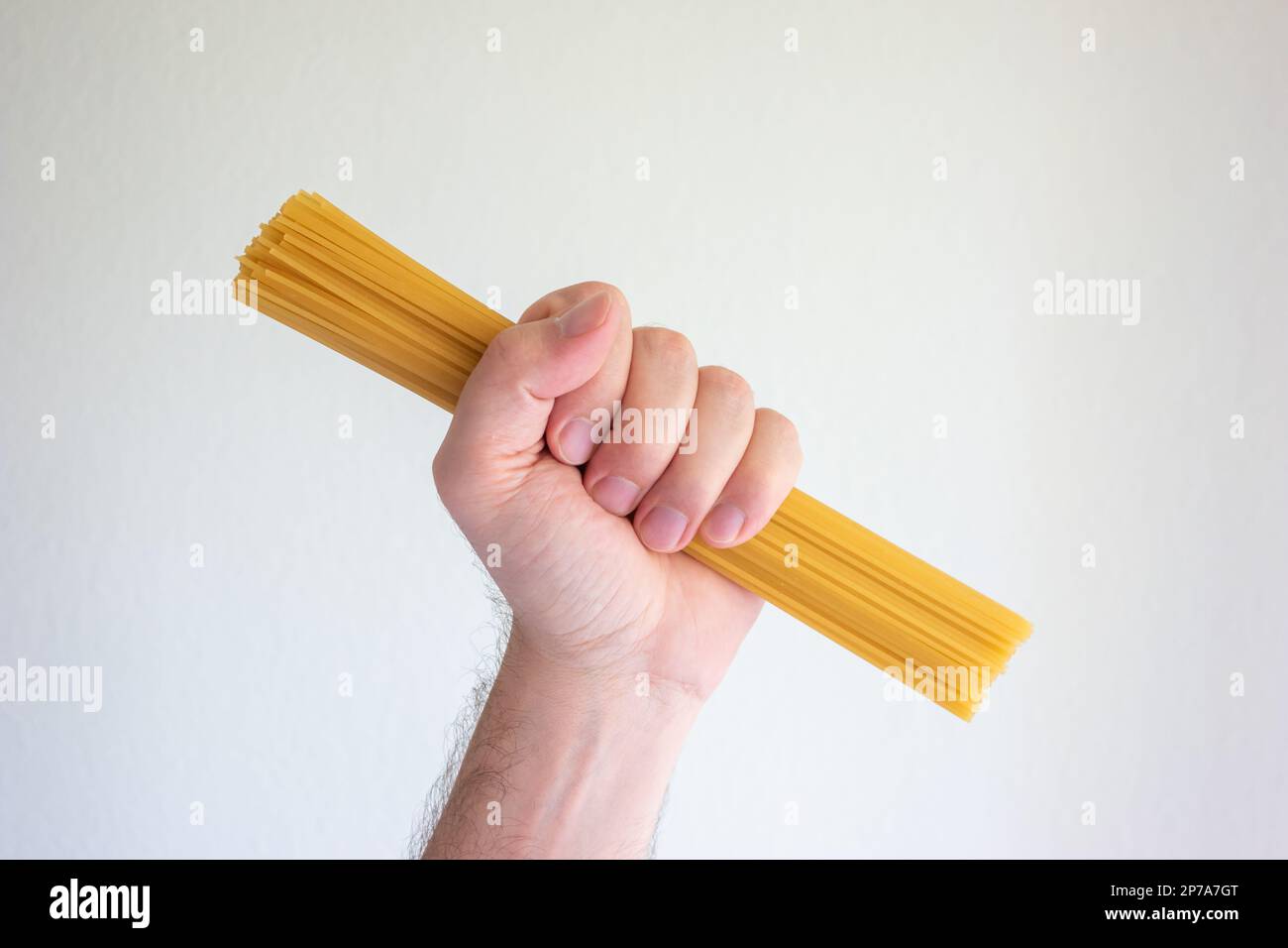 Caucasian male hand holding a stack of raw long spaghetti close up shot ...