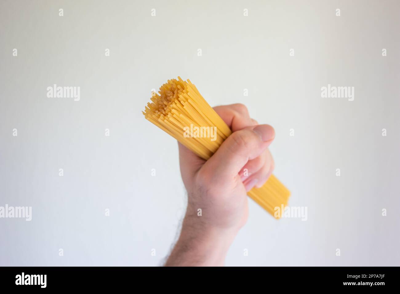 Caucasian male hand holding a stack of raw long spaghetti close up shot ...