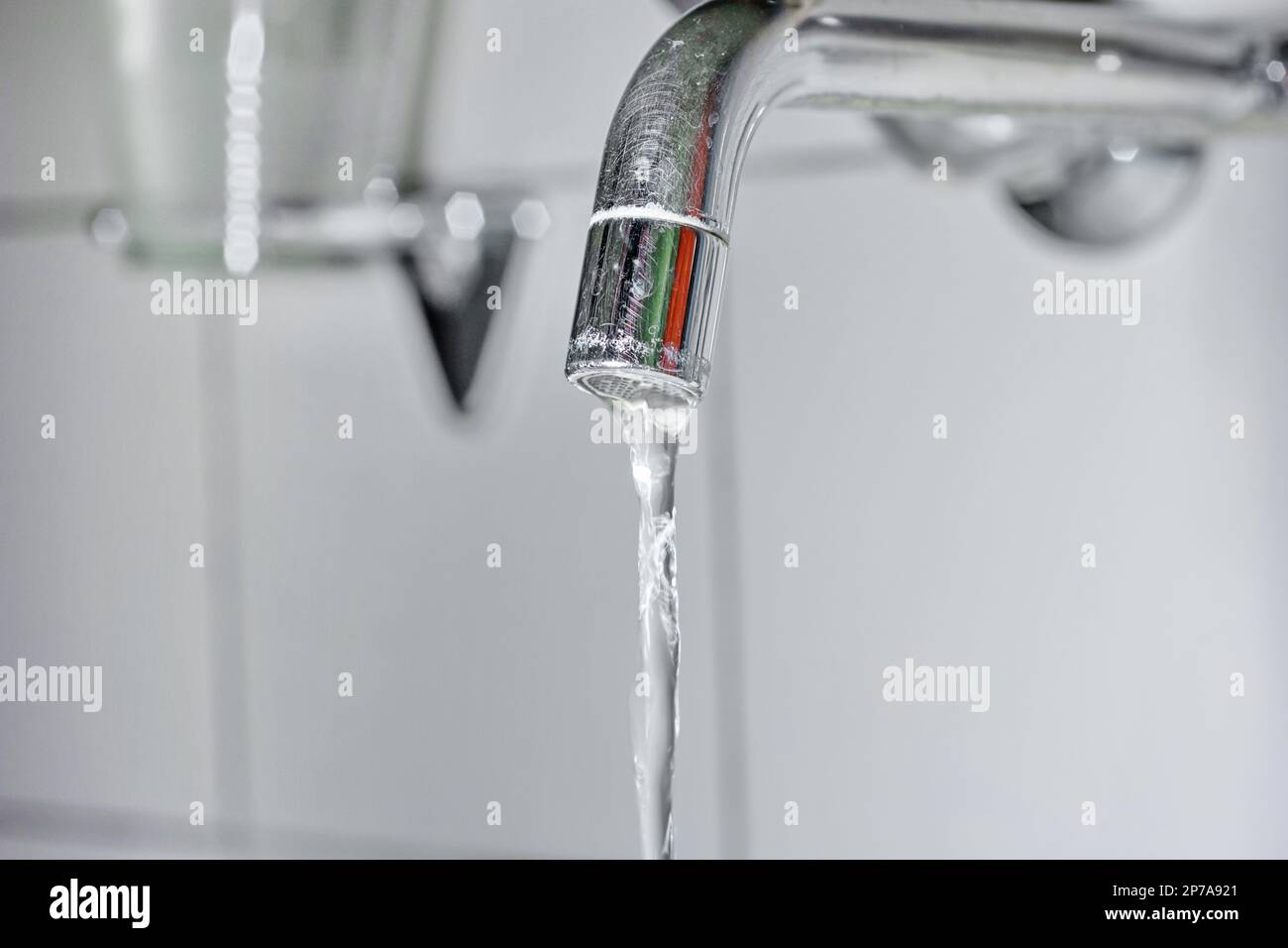 Bathroom sink faucet tip with flowing stream of water. Macro close up ...