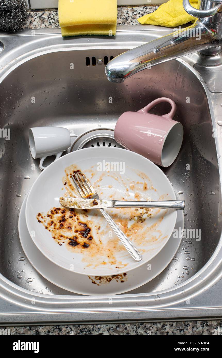 Dirty dishes in the kitchen sink. Food sauce stained porcelain dishes ...
