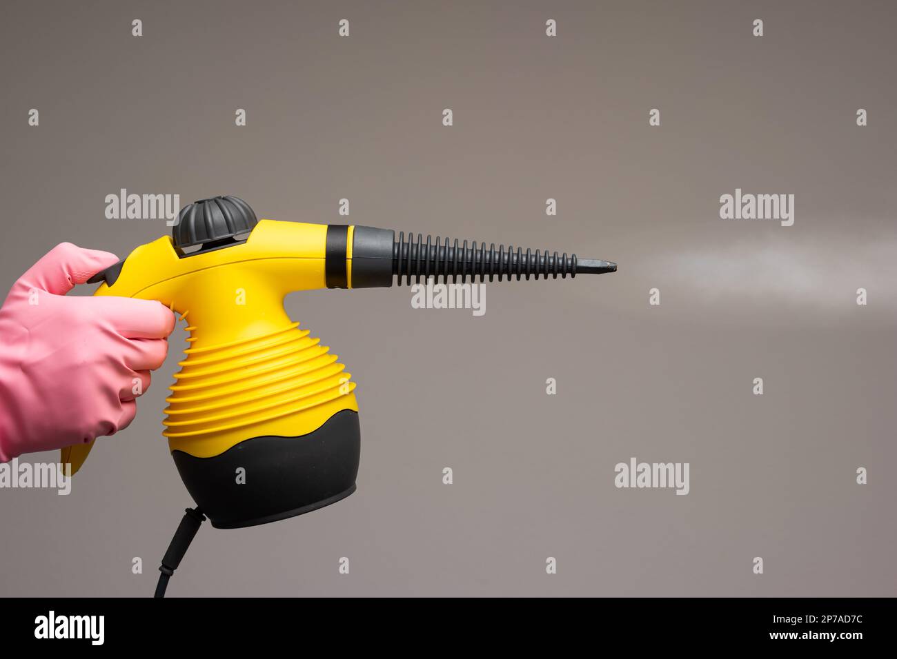 Male hand in rubber glove holding a small steam pressure cleaner. Close ...