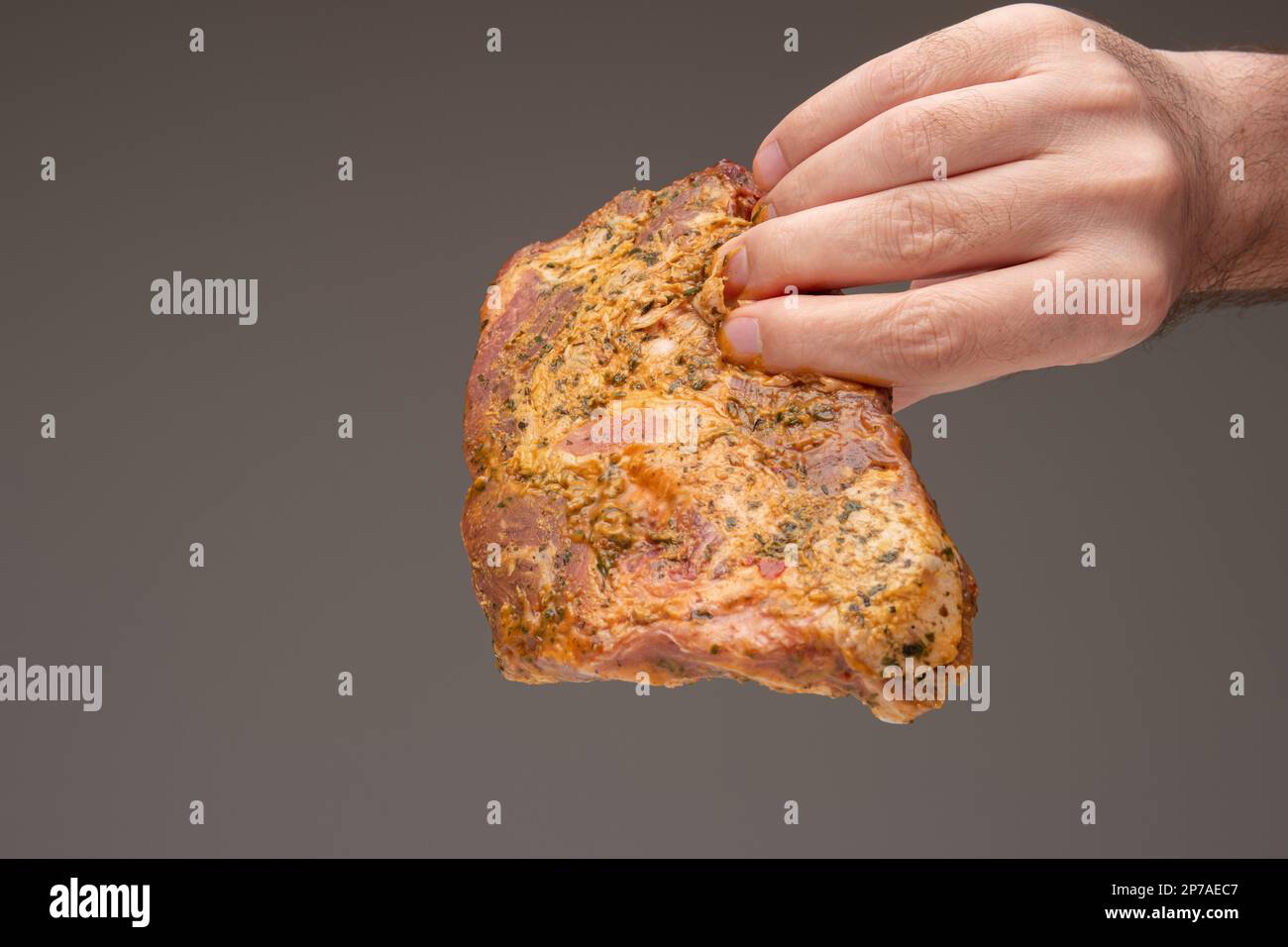 Raw rack of seasoned pork ribs held in male hand close up shot ...