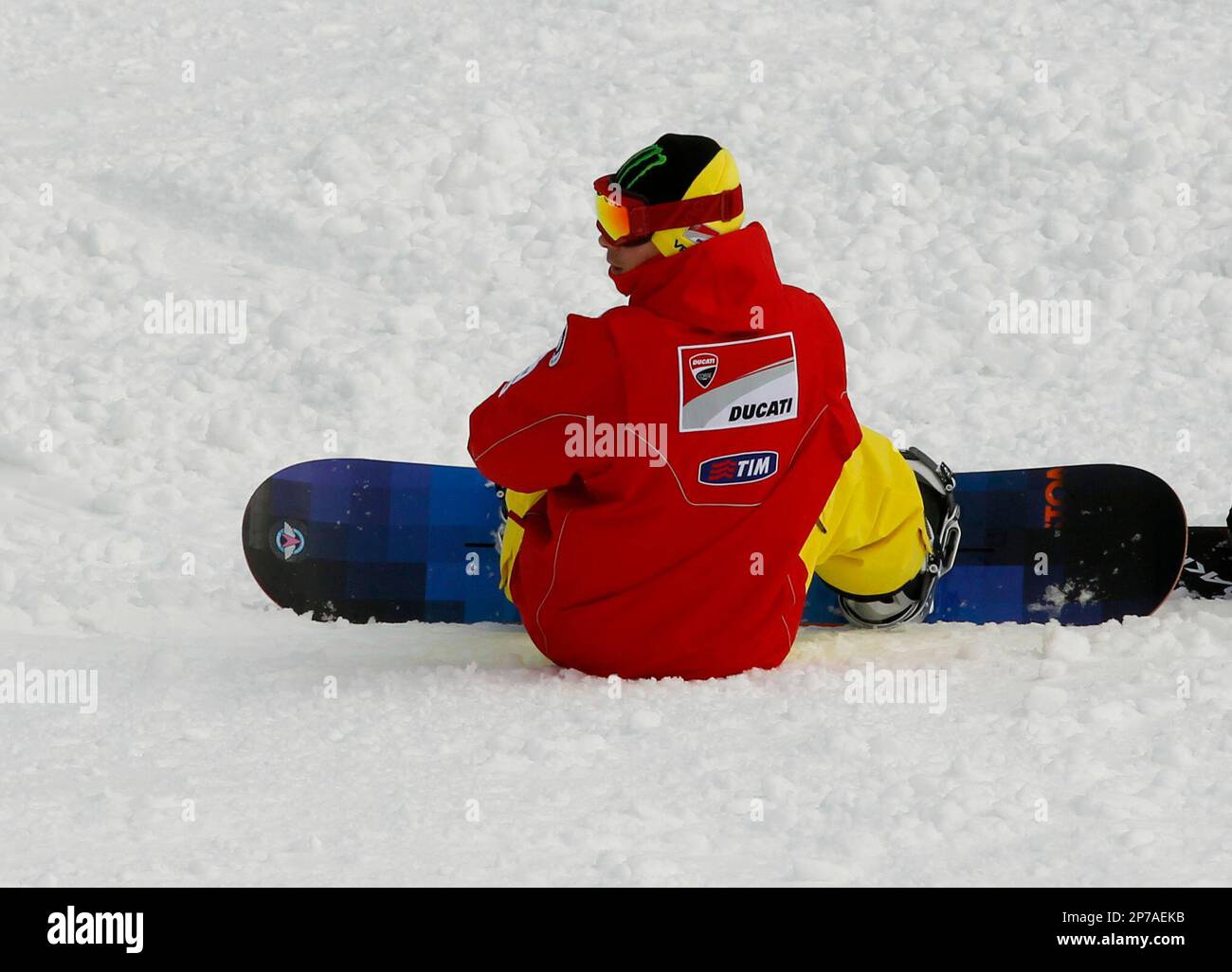 Italian Ducati rider Valentino Rossi sits on the snow with a snowboard ...
