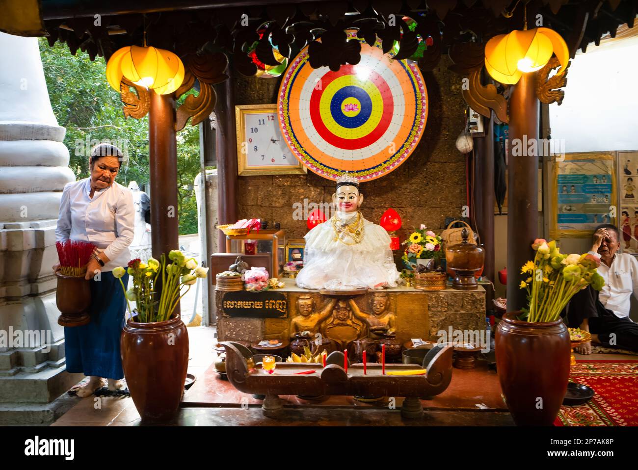 Two local Cambodian people at a small shrine at the back of Wat Phnom ...