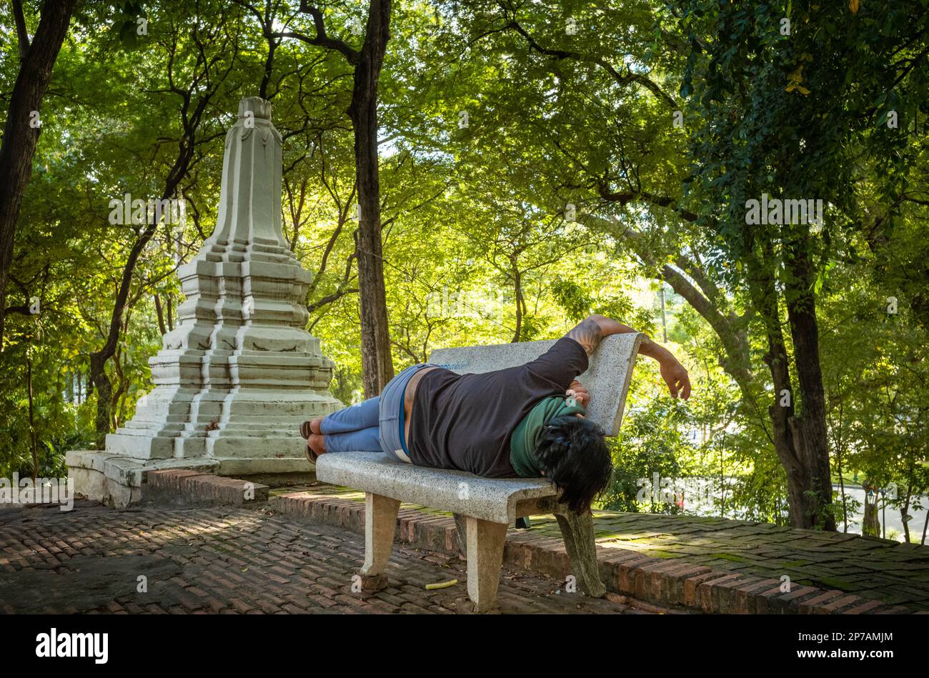 A Cambodian man sleeps on a bench in the grounds of Wat Phnom in Phnom ...