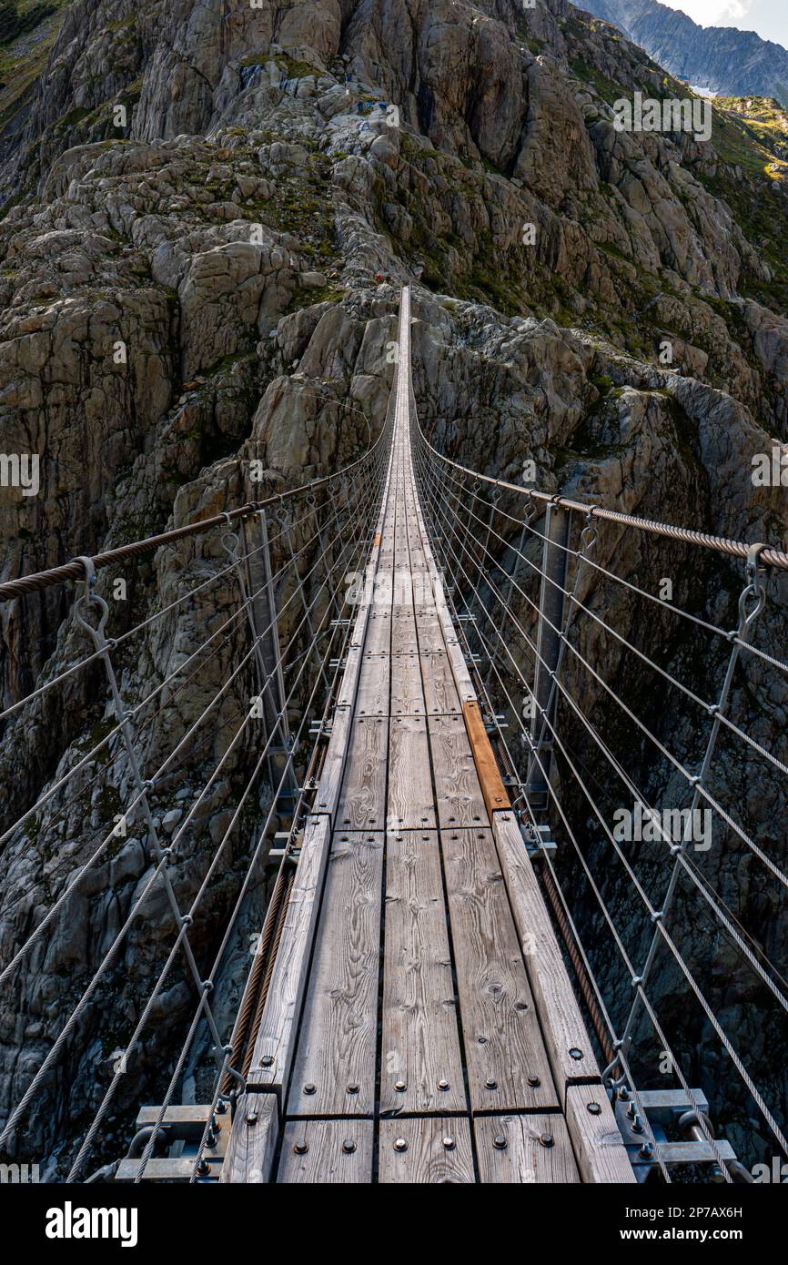 Wooden suspended cable narrow bridge in the Swiss Alps. Trift bridge ...