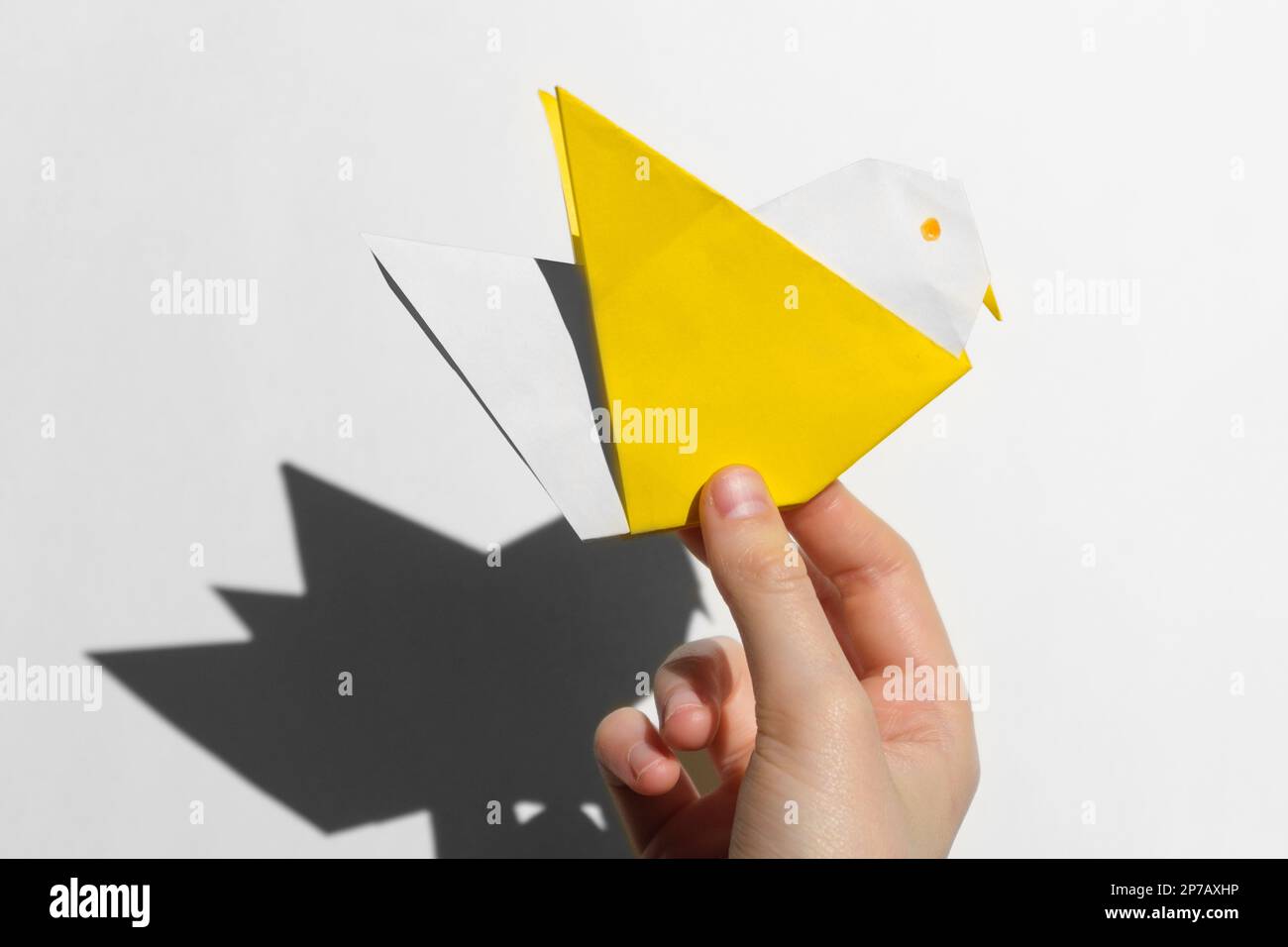 Children's hands do origami from colored paper on white background ...