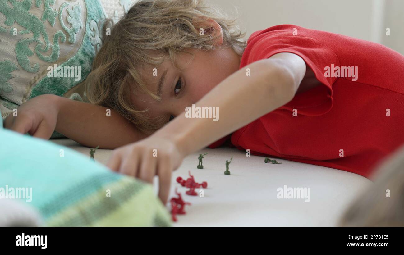 One small boy playing with toy soldiers. Child plays at home with tiny ...