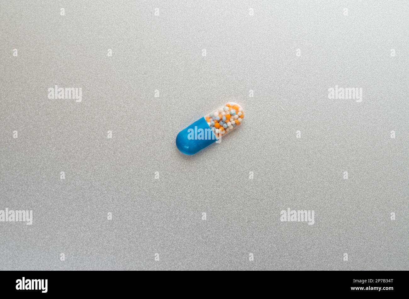 Half blue half clear medical capsule with colored small grains inside ...
