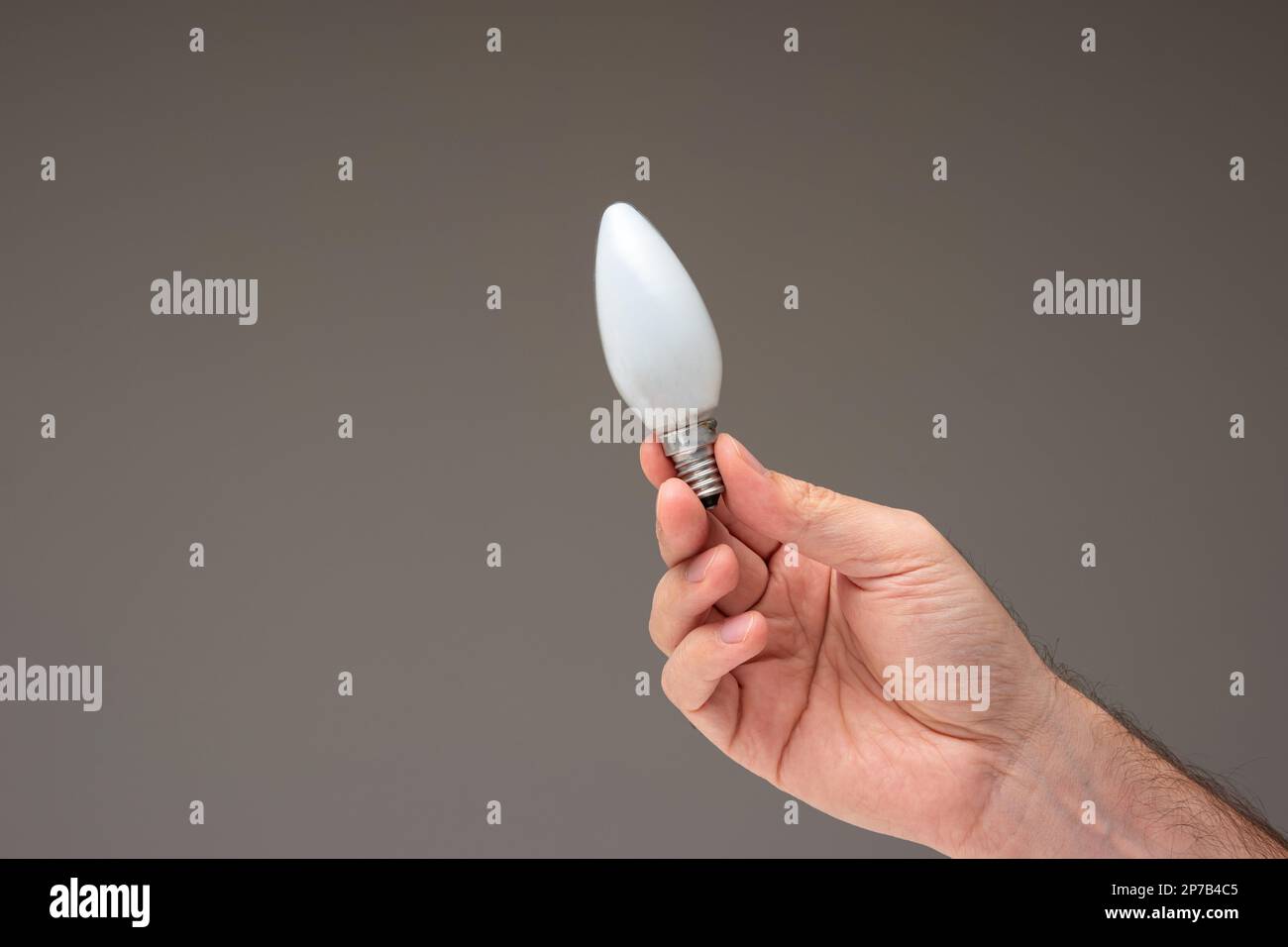 White mate incandescent light bulb held in hand by Caucasian male hand ...