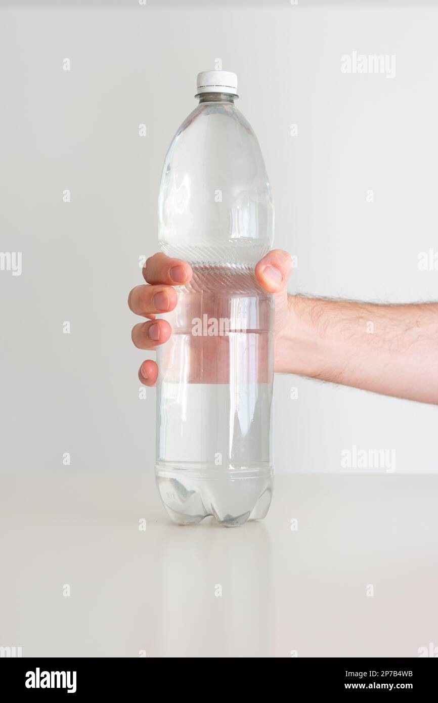 Large clear plastic water bottle with close cap held by unrecognizable ...