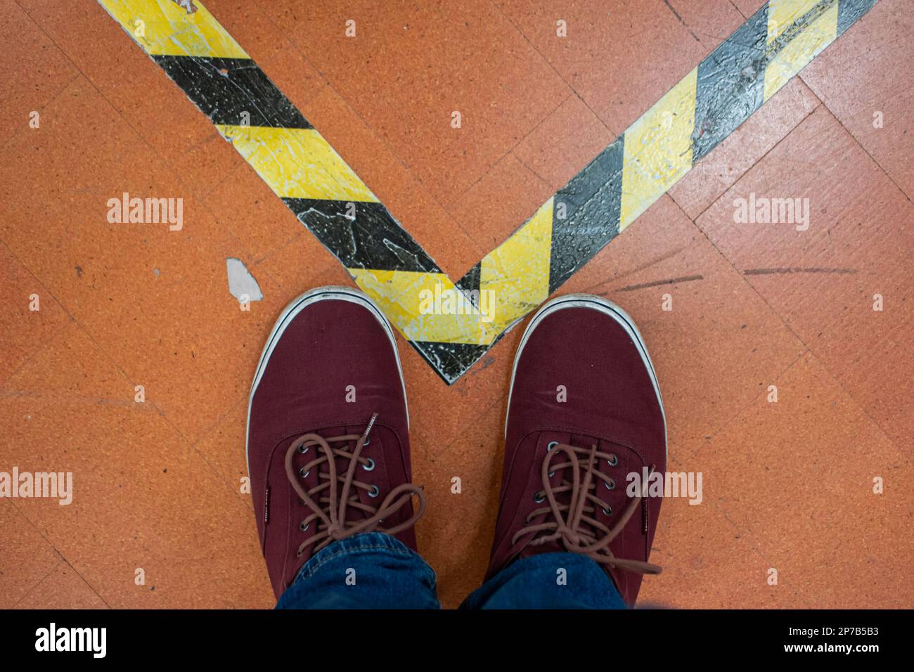 2 feet standing behind a security line sticker on a floor inside ...