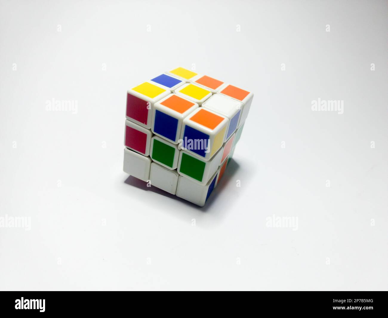 A classic Rubik's Cube displayed on a white, square-patterned surface ...
