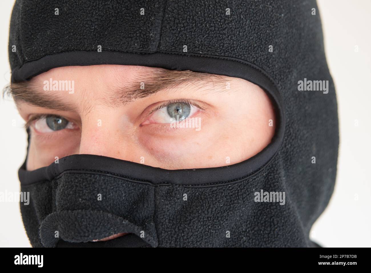 Caucasian male face wearing a black fabric ski mask. Close up shot ...