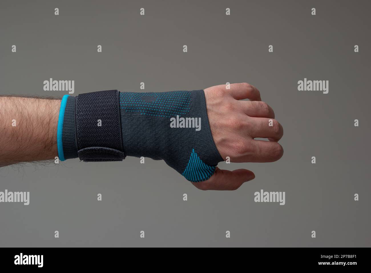 Velcro wrist stabilizer cast worn by Caucasian male hand. A blue split ...