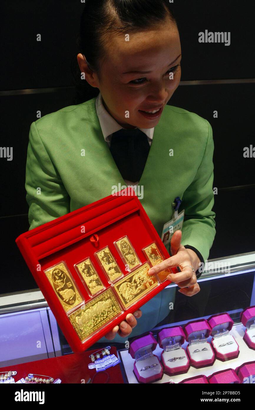 A sales person holds up gold bars to show customers at a store in ...