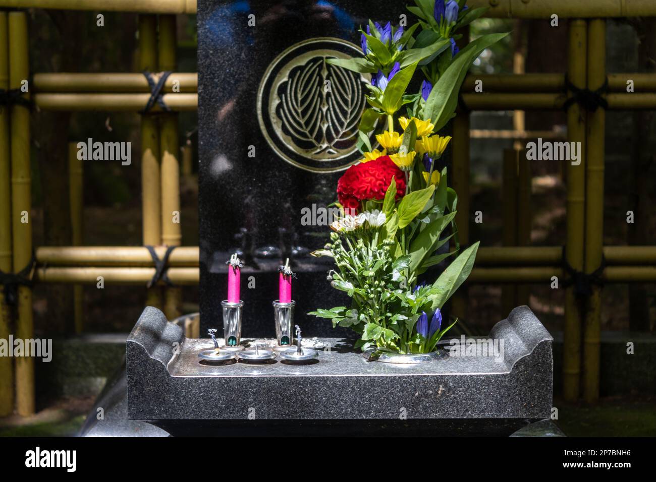 Traditional offering of flowers, incense and candles placed on a tomb ...