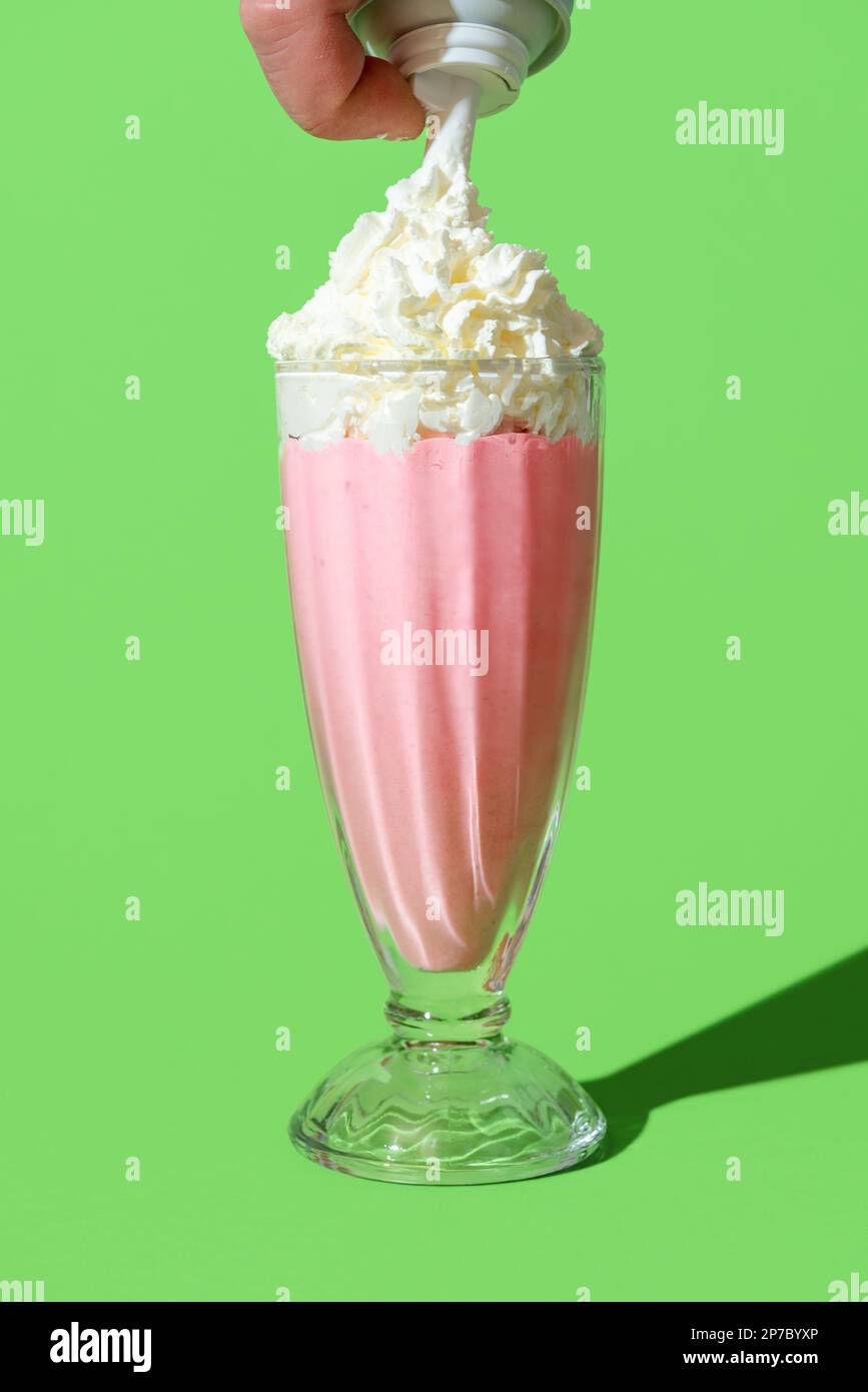 Strawberry milkshake glass in bright light, minimalist on a green ...