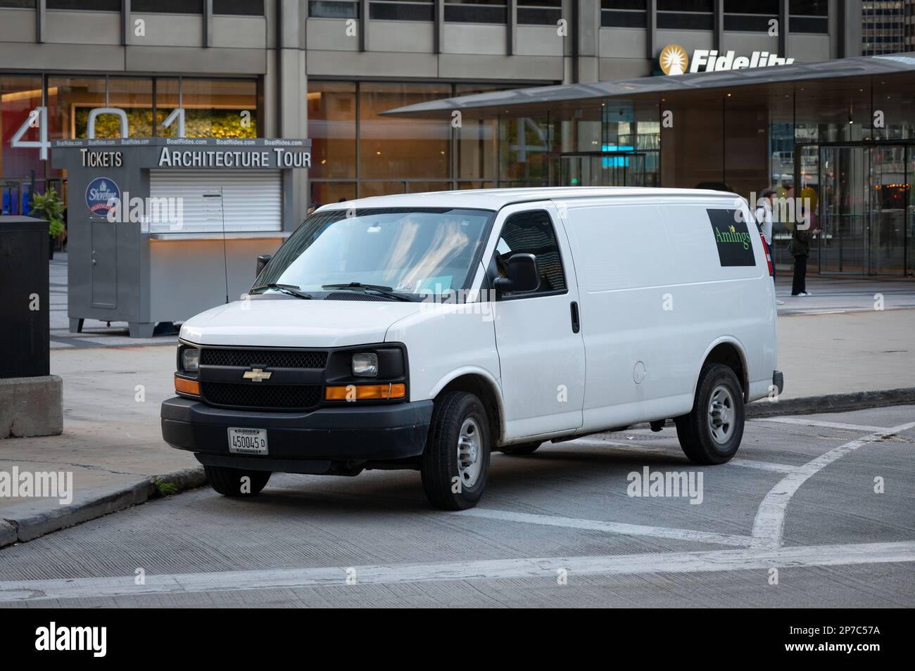 A white commercial van parked at the corner of a busy city street Stock ...