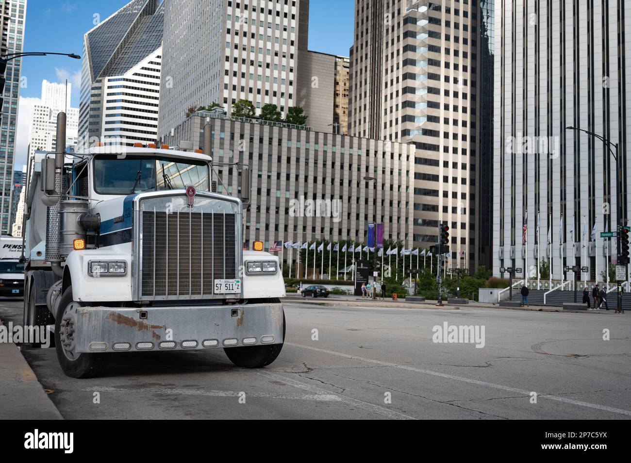 A large commercial truck drives down a street in the city, surrounded ...