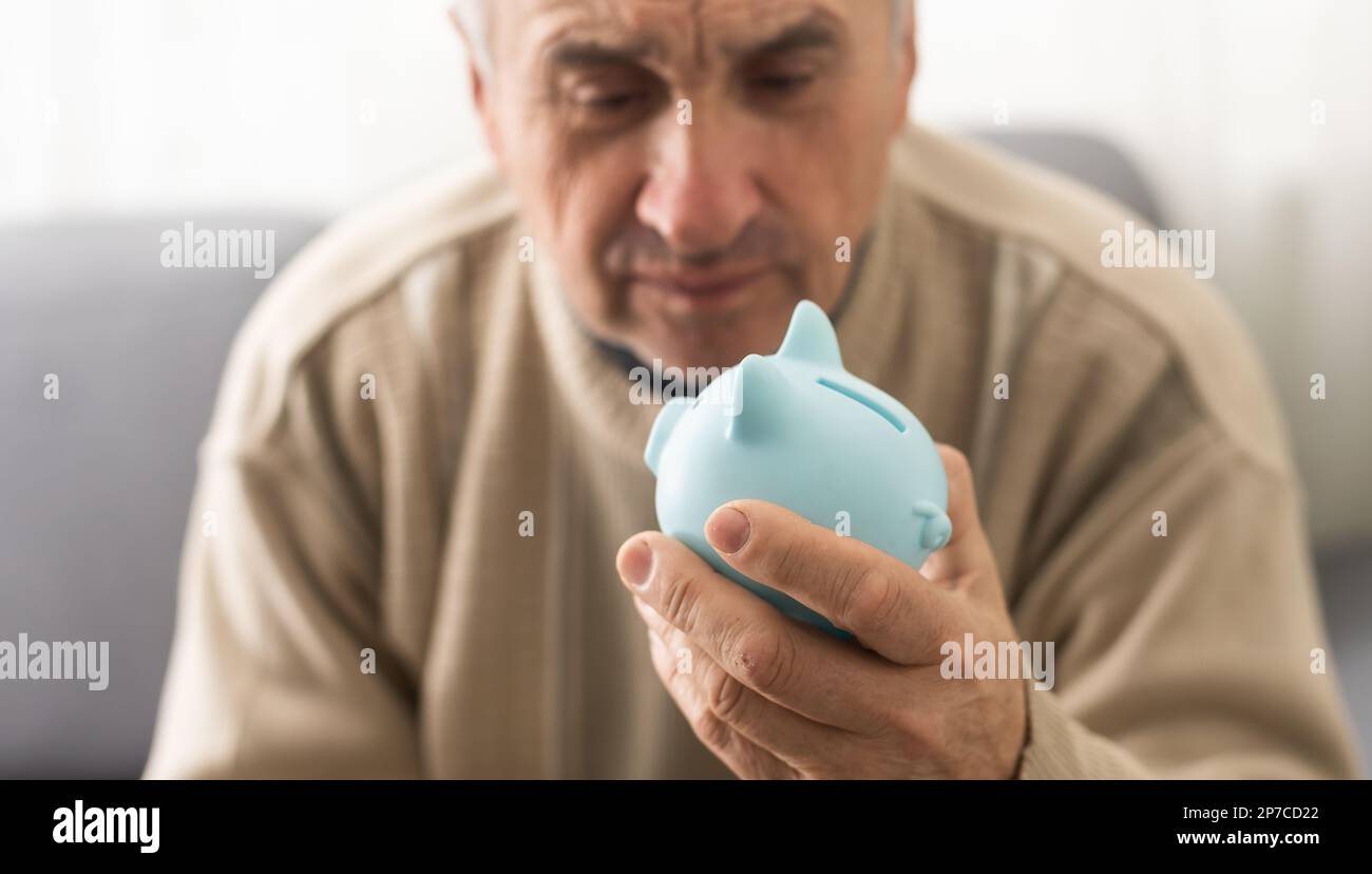 Senior caucasian man holding piggy bank with glasses depressed and ...