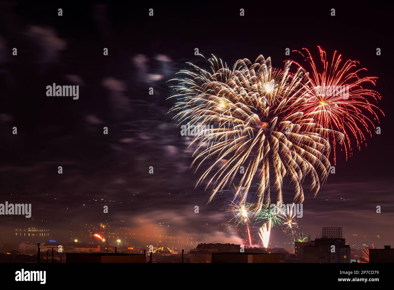 Colorful fireworks display over city. White red firework bursts in the ...