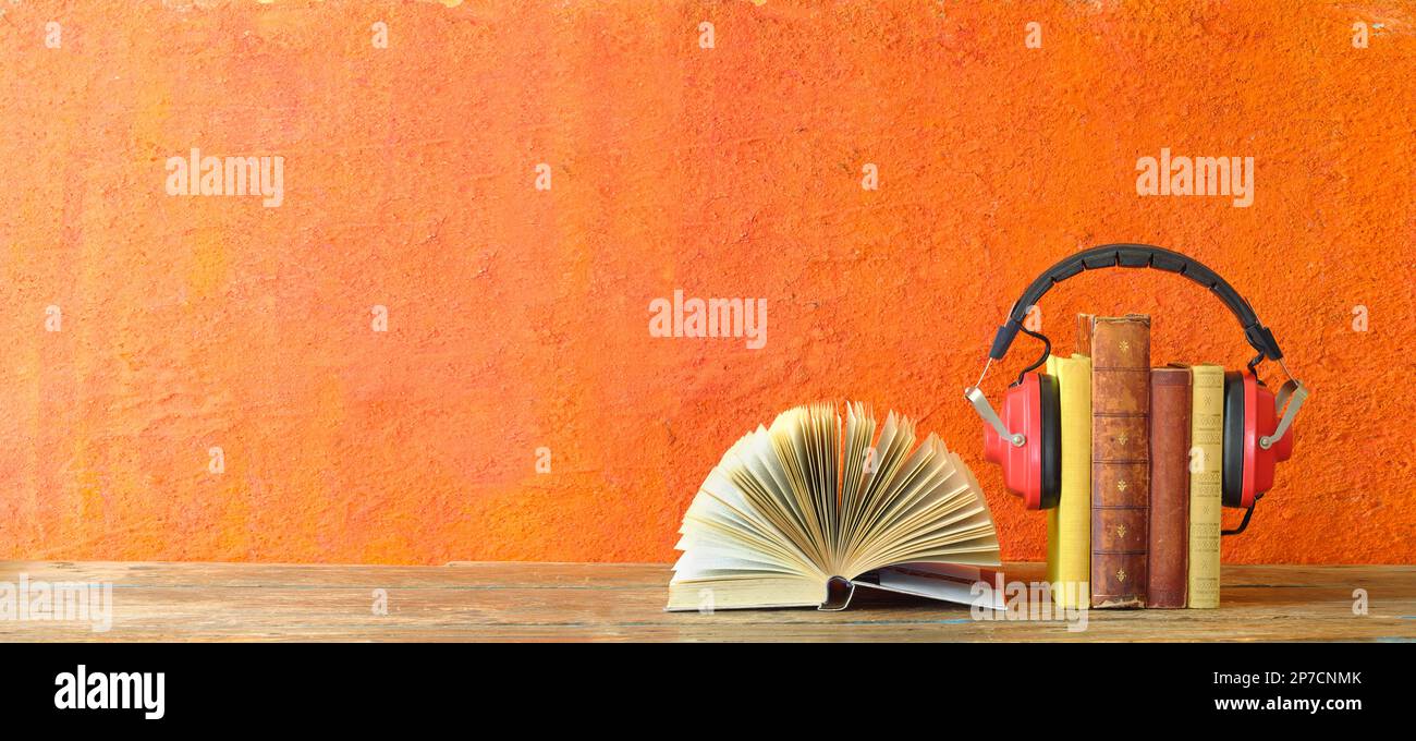 audio book concept with row of books, one opened and vintage headphones ...