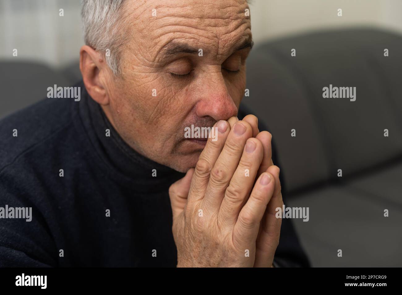 Please, Lord. Nervous worried aged Caucasian man praying on couch at ...