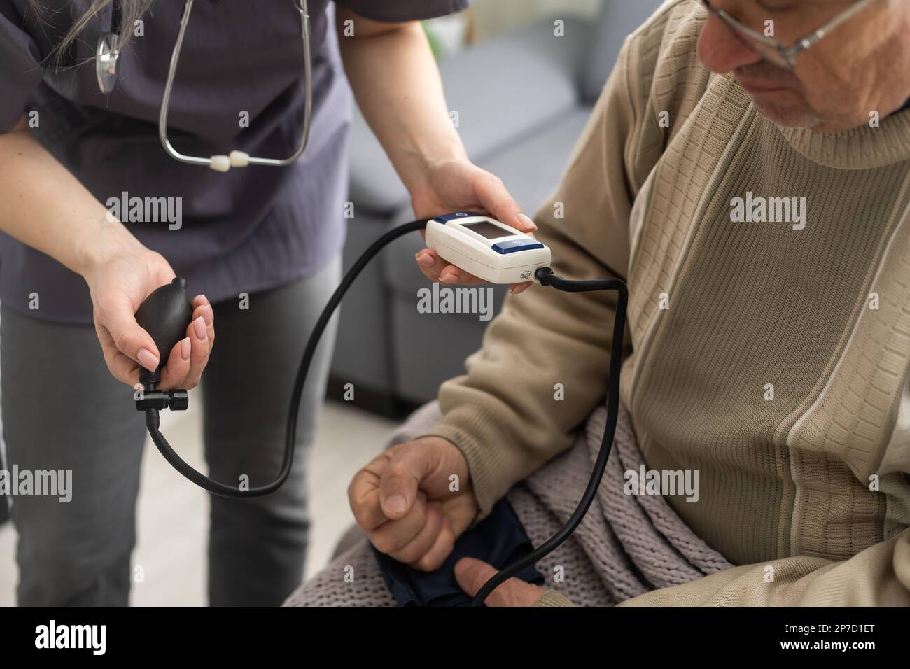 Nurse measure high blood pressure of a sick senior mature male patient ...
