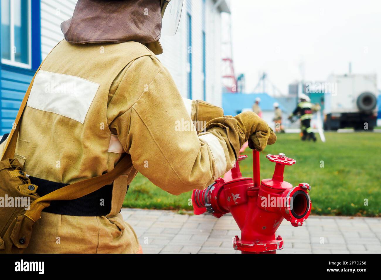 Fire rescuer in helmet and protective clothing sits next to fire ...